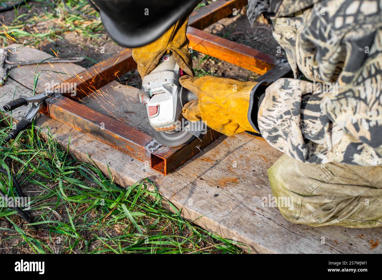 A welder in a helmet processes a weld seam on a metal profile using a ...