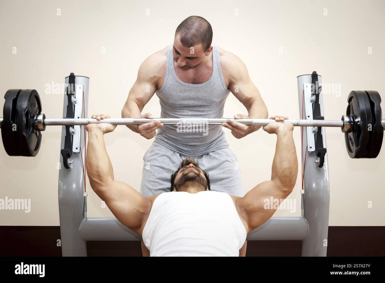 A handsome young muscular sports man doing bench press with a little ...