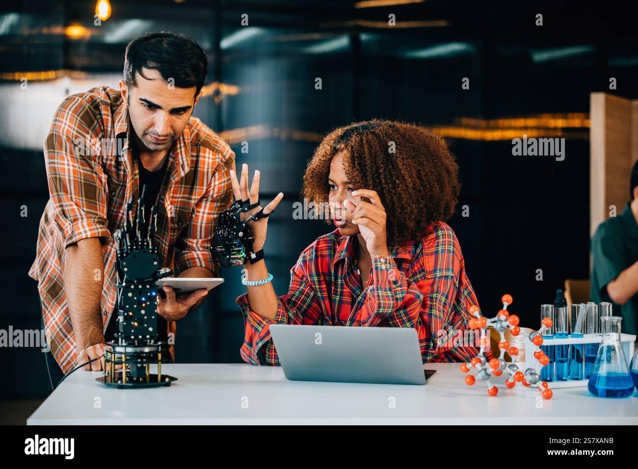 Teacher assists student building a robotic arm in classroom for design ...