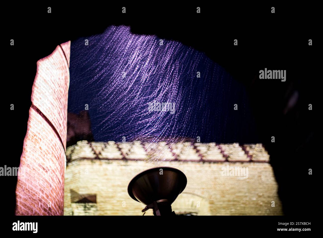 Rainfall illuminated in front of historical monastery walls at night in ...