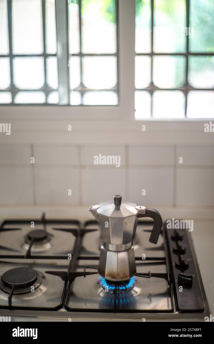 Traditional stovetop coffee maker in use on a gas stove for morning ...