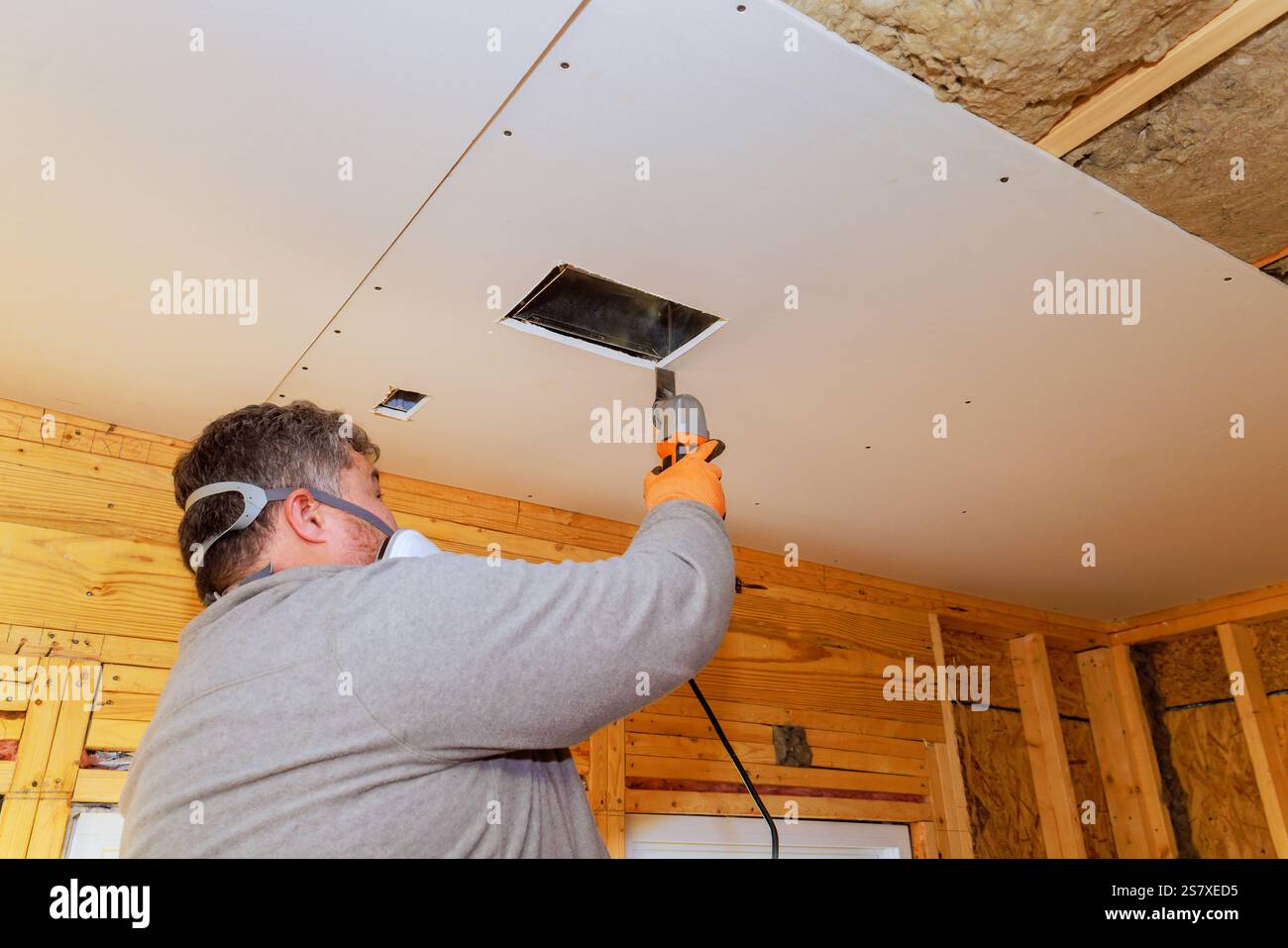 Contractor worker uses saw tool to install ventilation duct while ...