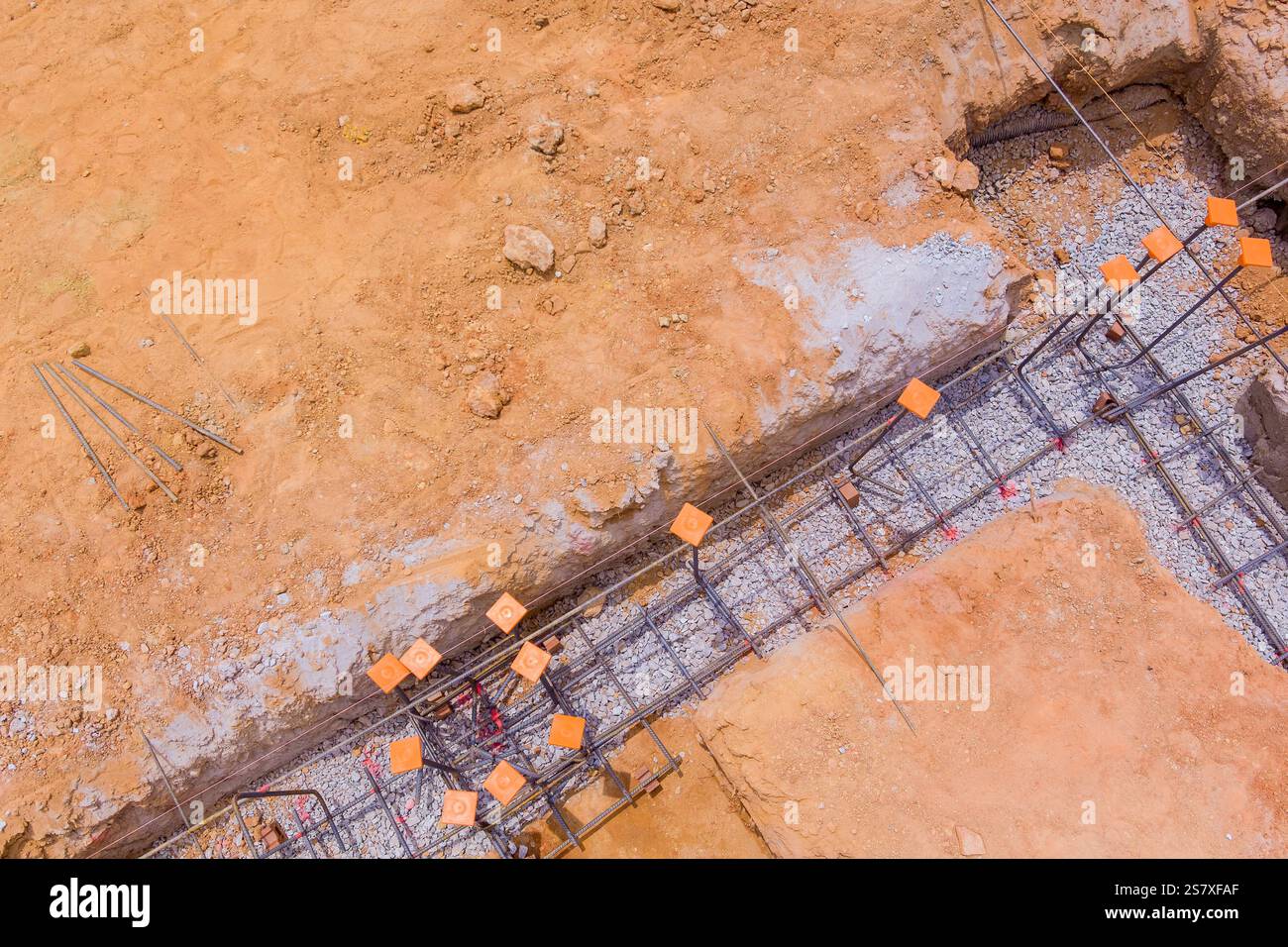 Workers are laying rebar, gravel in trenches for foundation at ...