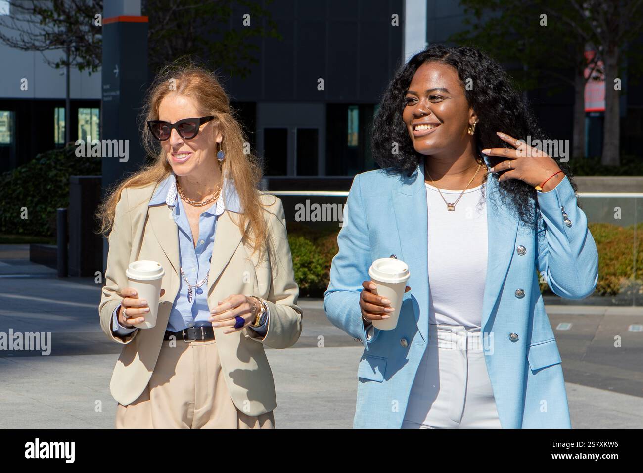 two women of different ages stroll while having coffee after work. High ...
