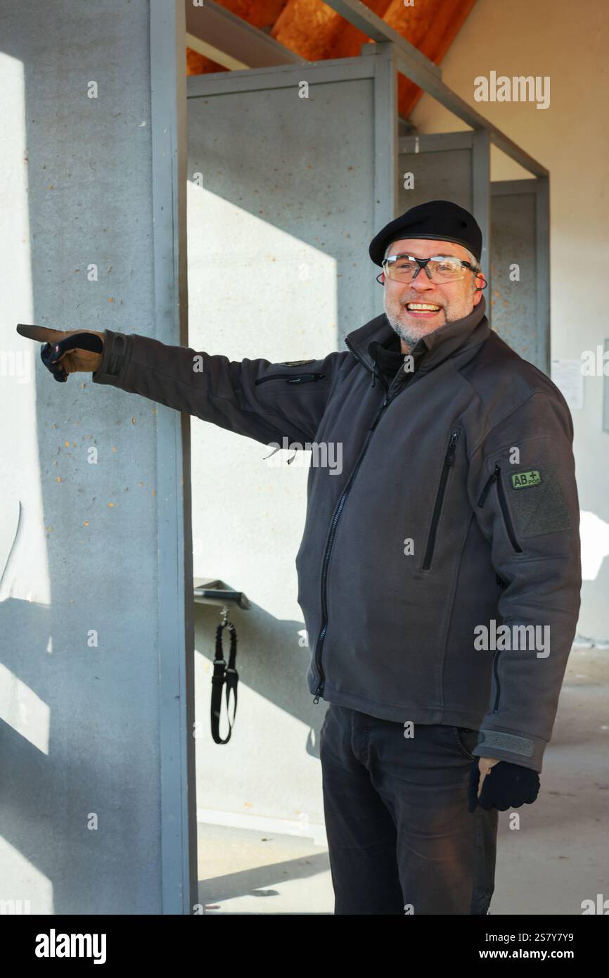 An instructor of shooting in a beret at a shooting range shows where to ...