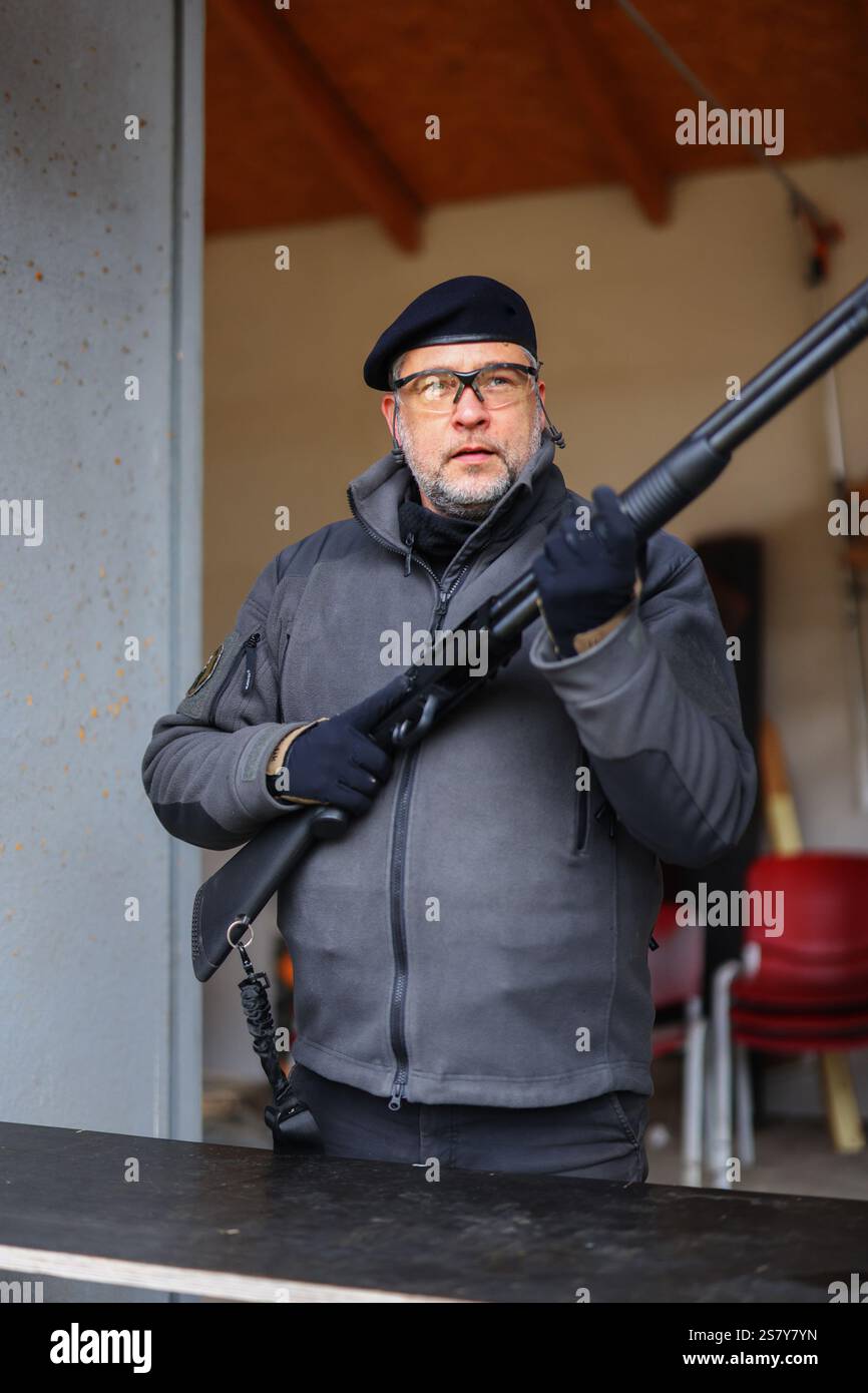 An instructor of shooting in a beret at a shooting range show how to ...