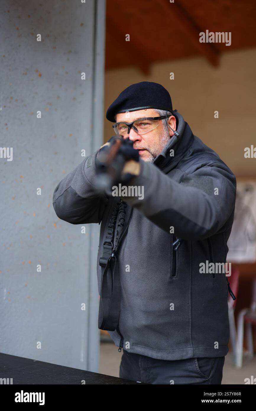 An instructor of shooting in a beret at a shooting range aims straight ...