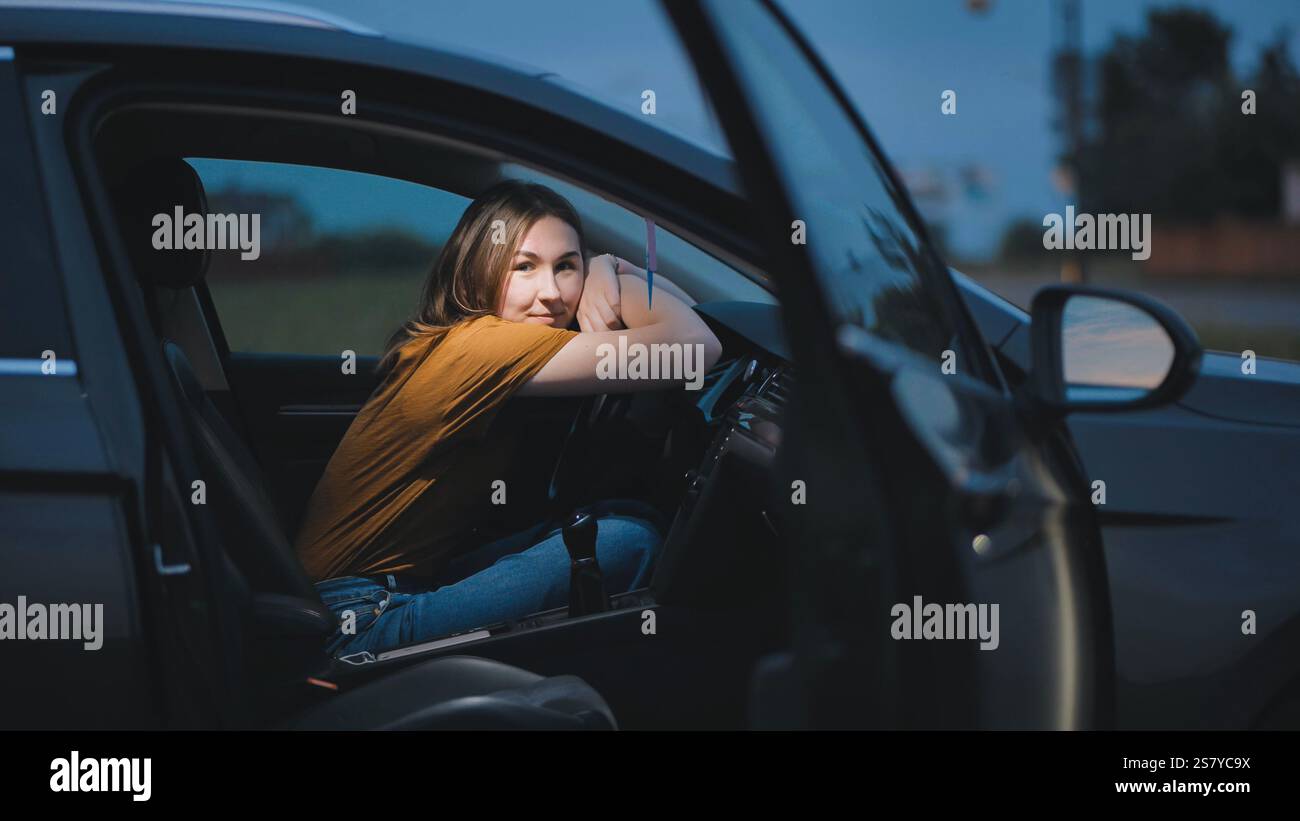Peaceful female driver leaning on steering wheel, relaxing inside open ...