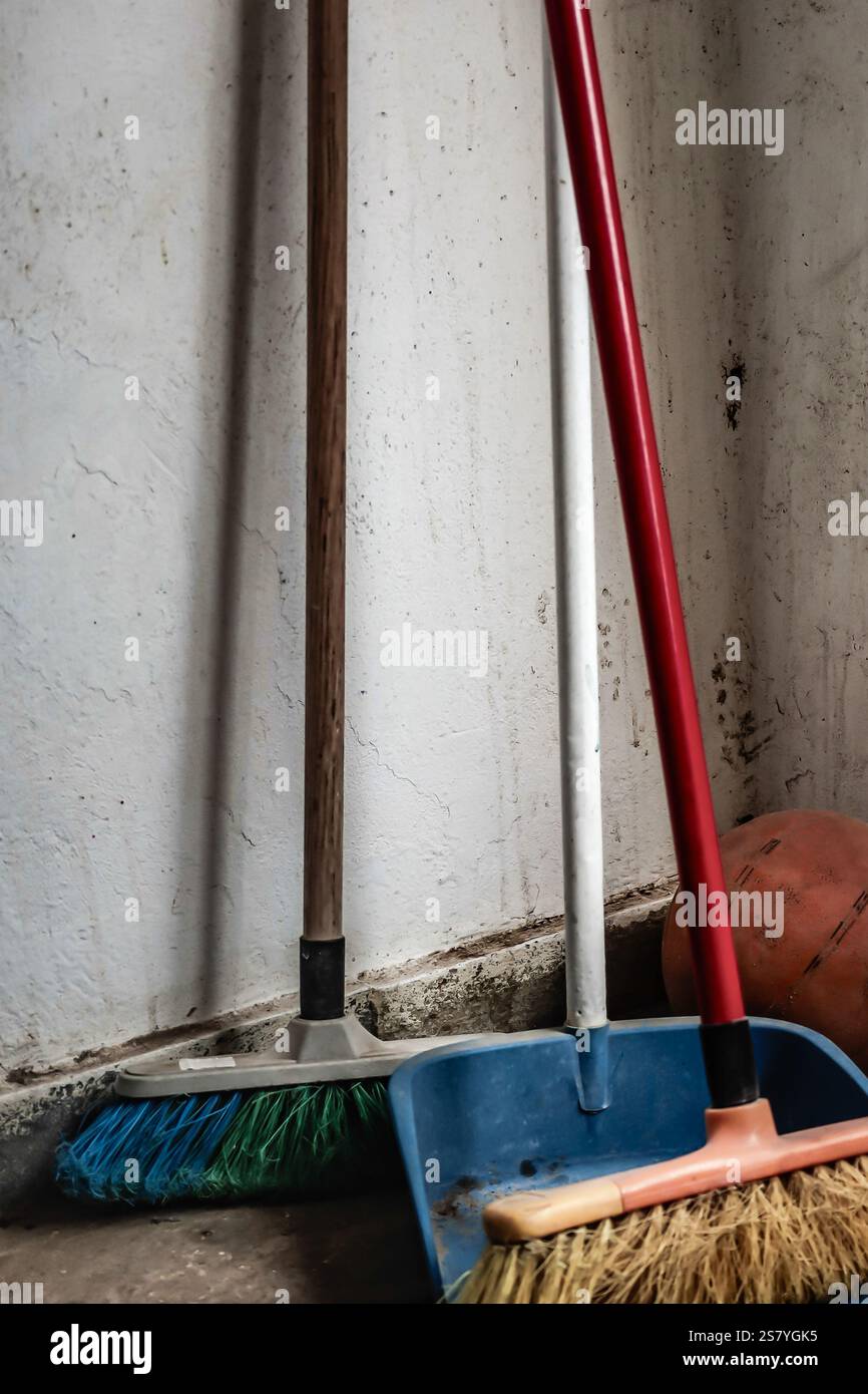 a rustic corner featuring cleaning tools, including a red-handled broom ...