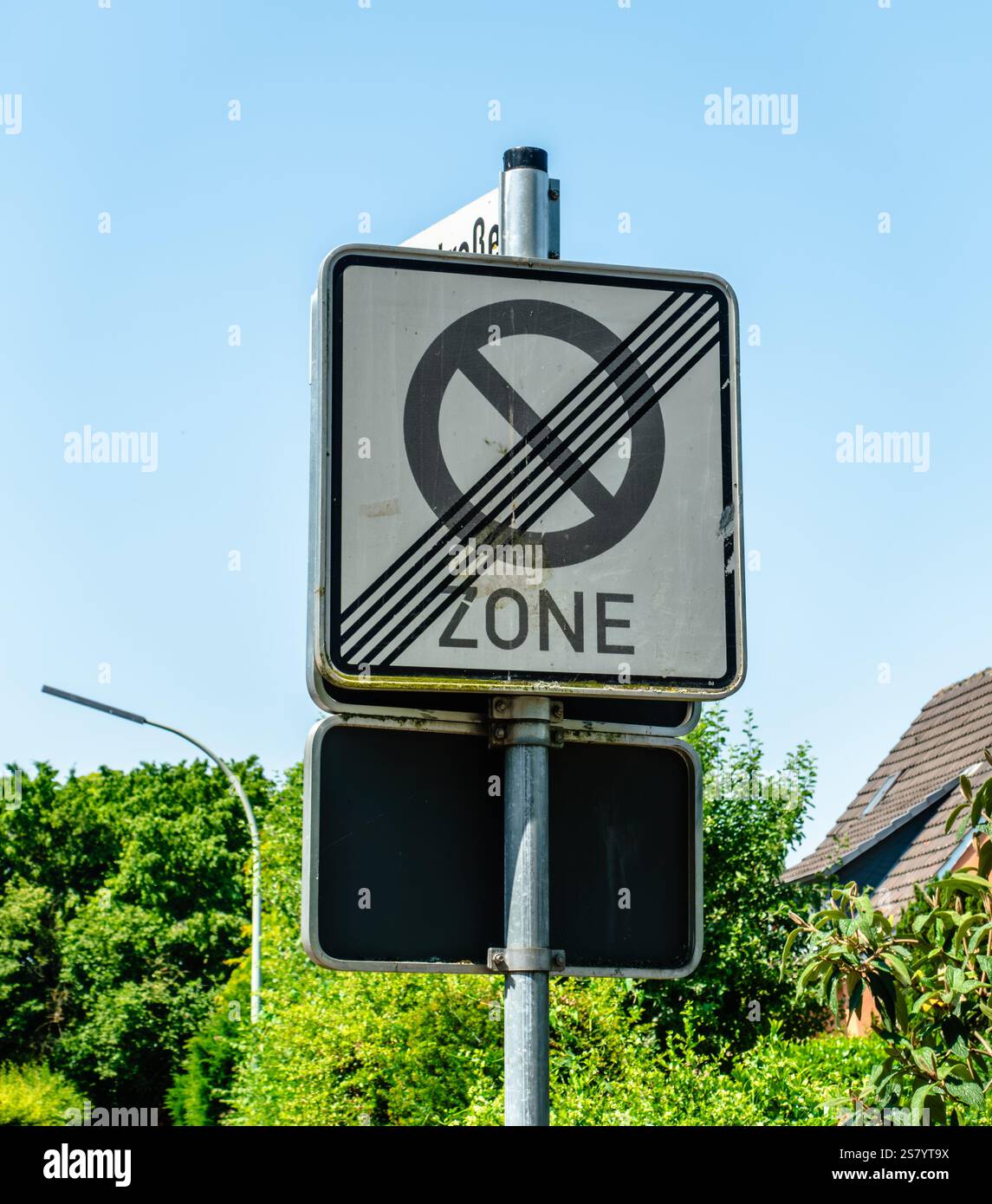 A no zone sign is on a pole in front of a house. The sign is black and ...