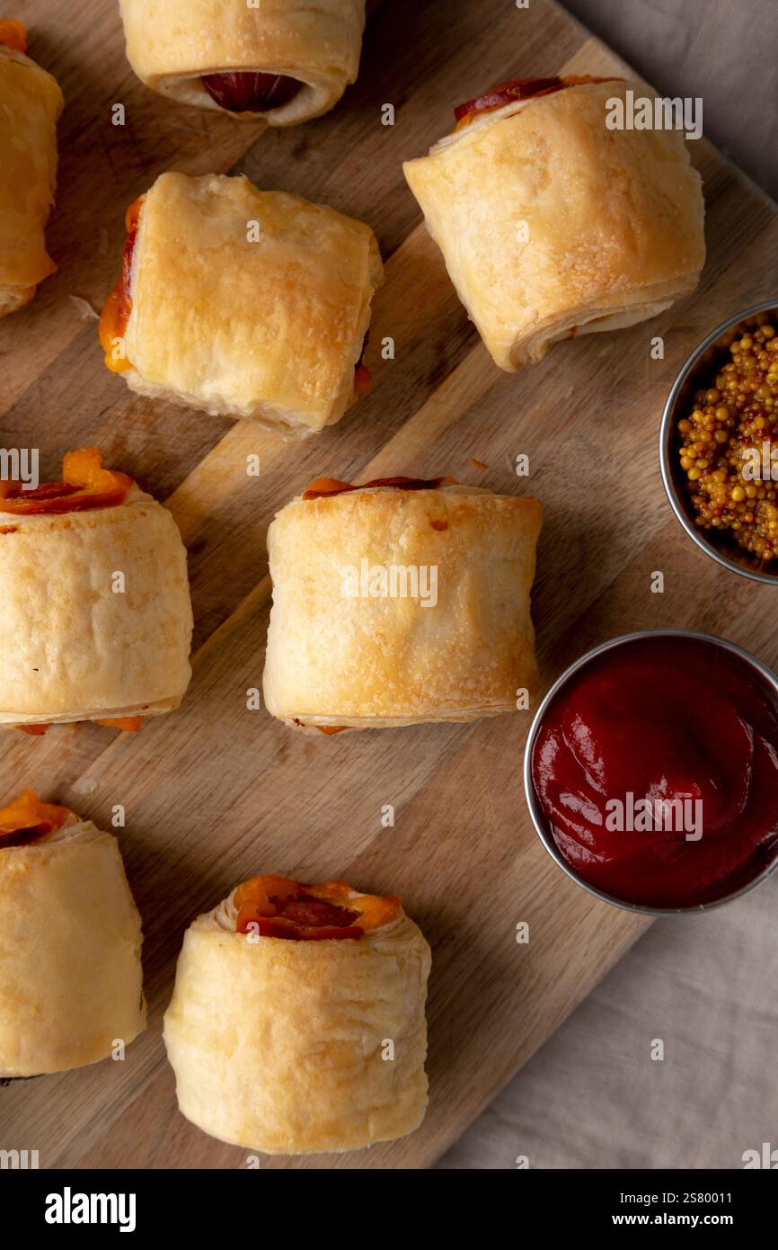 Homemade Pigs in a Blanket with Ketchup and Mustard on a Wooden Board ...