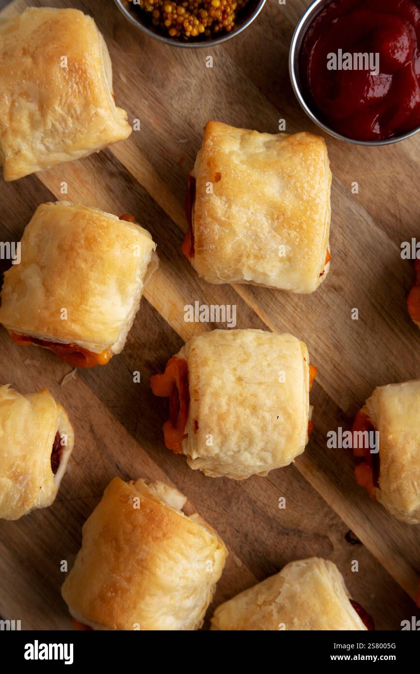 Homemade Pigs in a Blanket with Ketchup and Mustard on a Wooden Board ...
