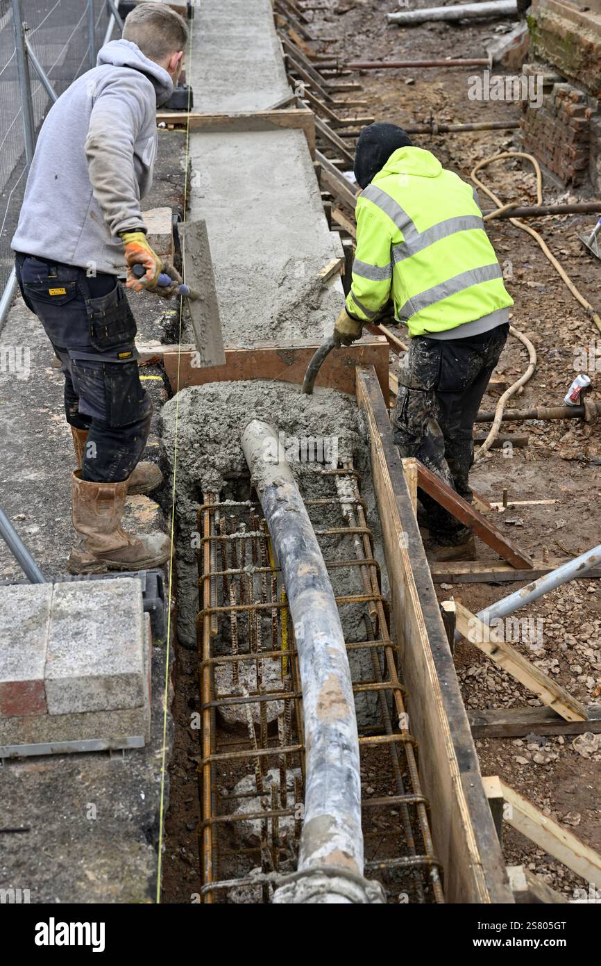 Concrete being pumped into timber formwork with steel reinforcing, two ...