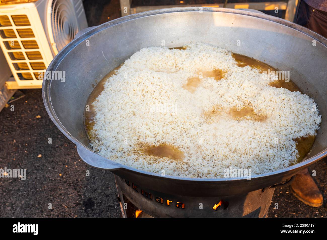 Cooking pilaf in a large pot. The stage of adding rice to the broth ...