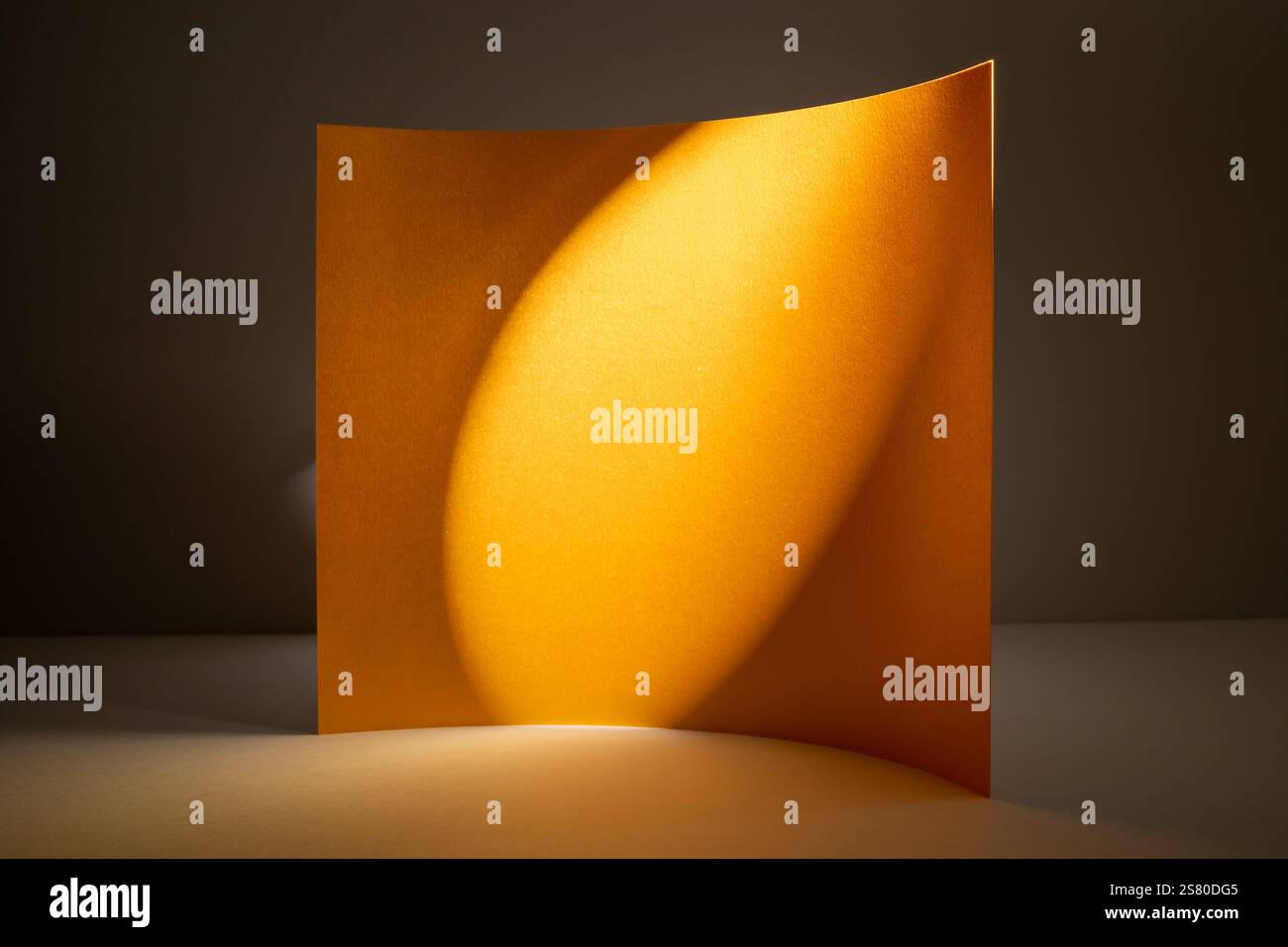A curved golden surface is illuminated by directed light, creating a ...
