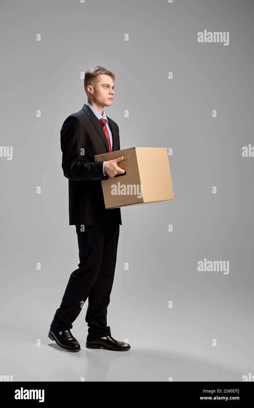 Man walking forward while carrying cardboard box with focused ...