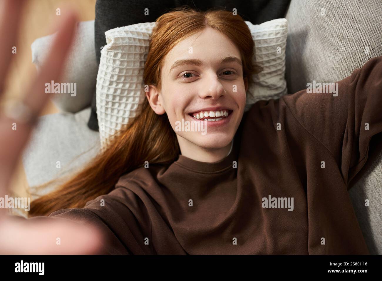 Bright smile radiates cheer as a young redhead relaxes in a stylish ...