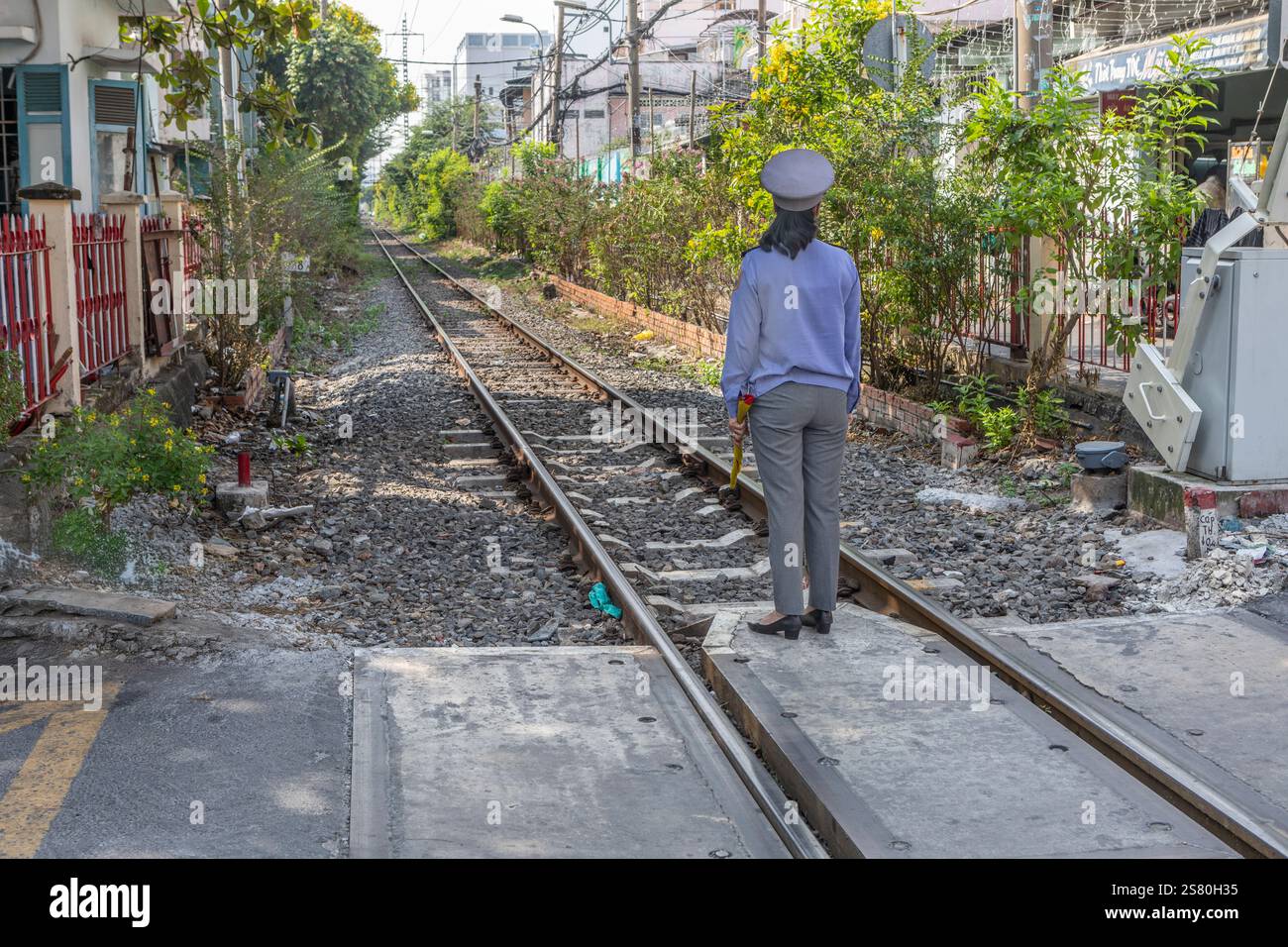 A lady guard on a level crossing on a section of the Saigon railway in ...