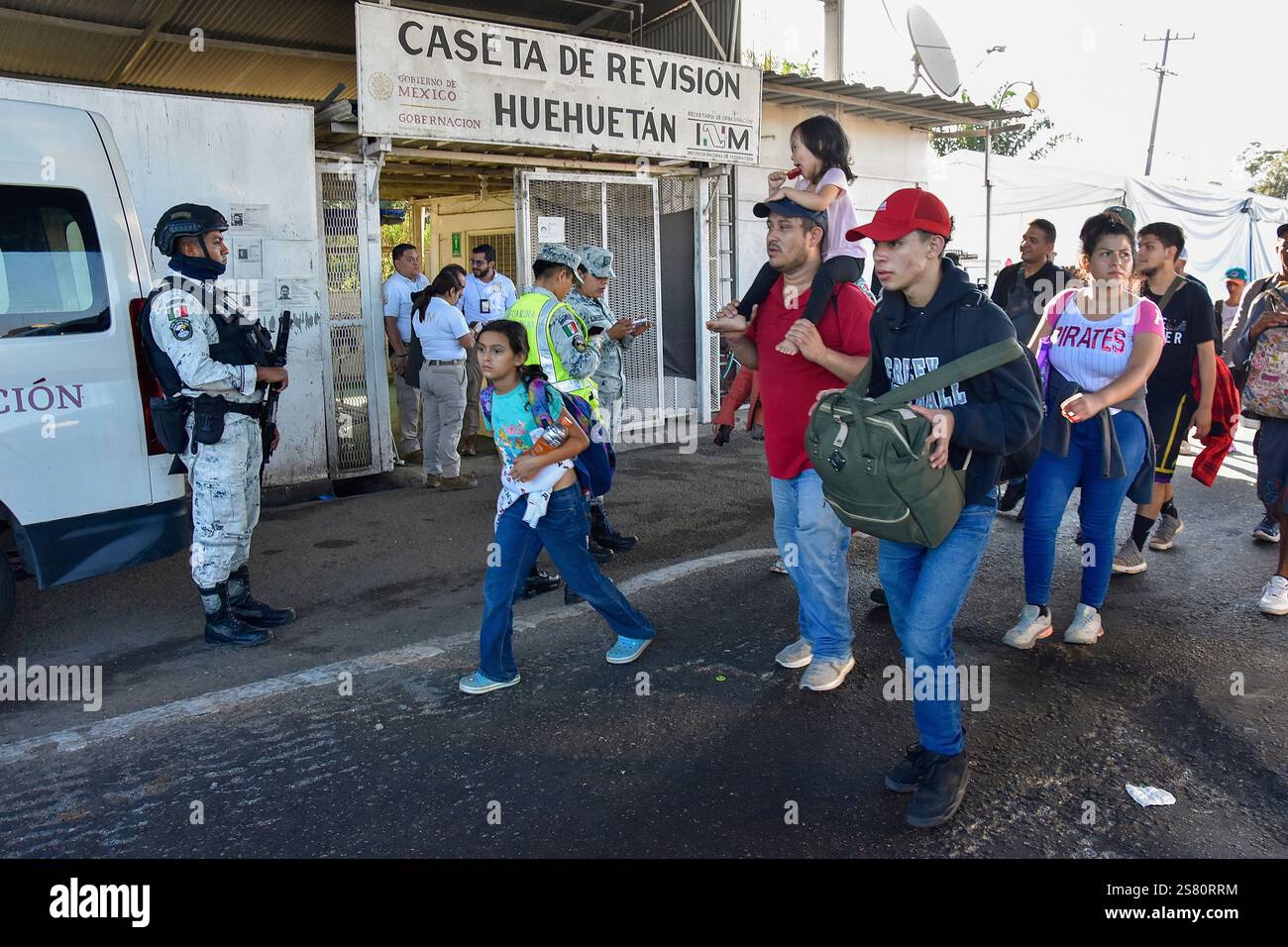 Migrants walk past a Mexican immigration checkpoint as they arrive to ...
