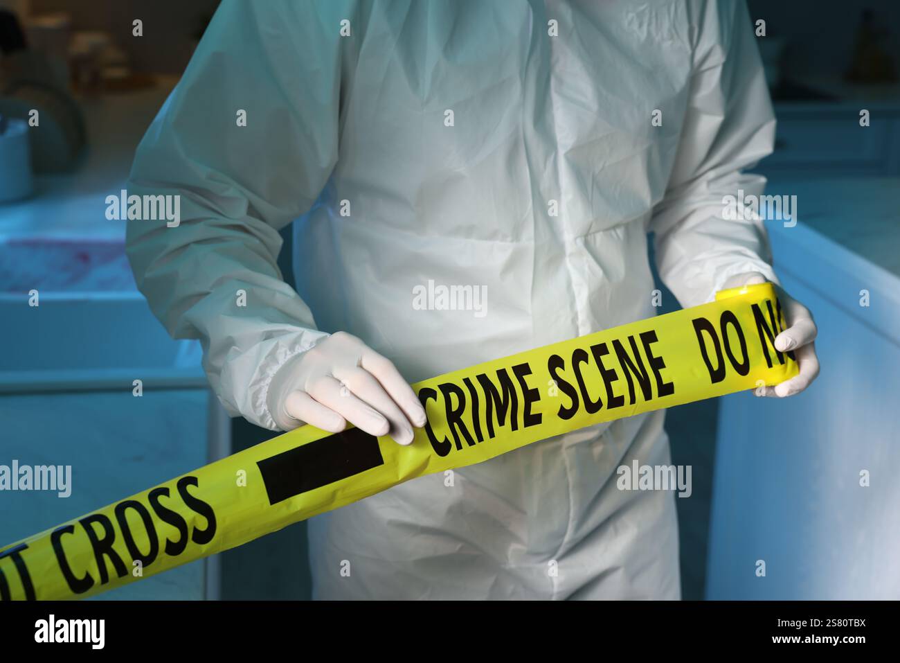 Forensic expert blocking way to crime scene with yellow tape indoors ...