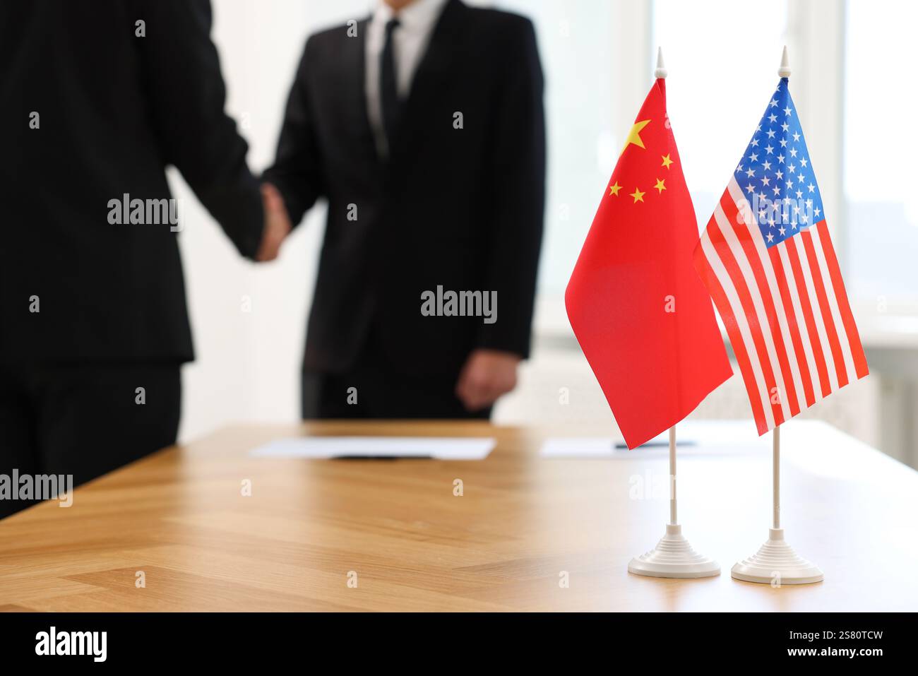 Diplomats shaking hands during meeting indoors, focus on flags of USA ...