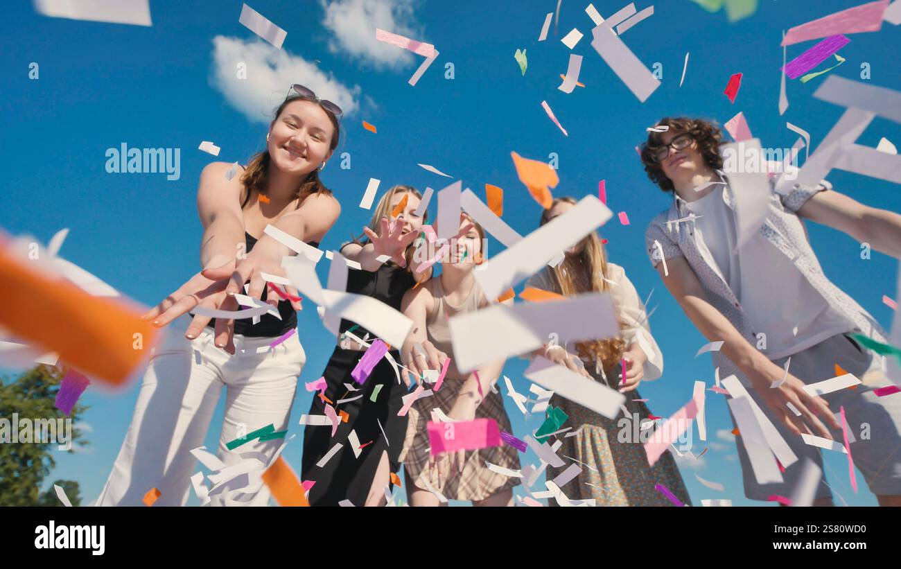 Group of cheerful high school students throwing colorful confetti in ...