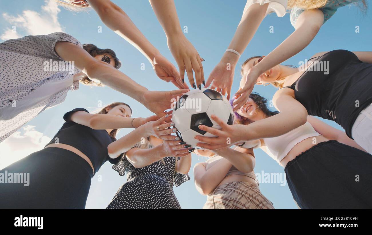 High school girls holding a soccer ball in a circle, representing teamwork and unity during ...