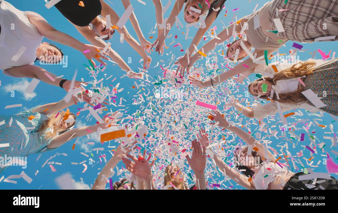 High school graduates joyfully tossing vibrant confetti in the air to ...