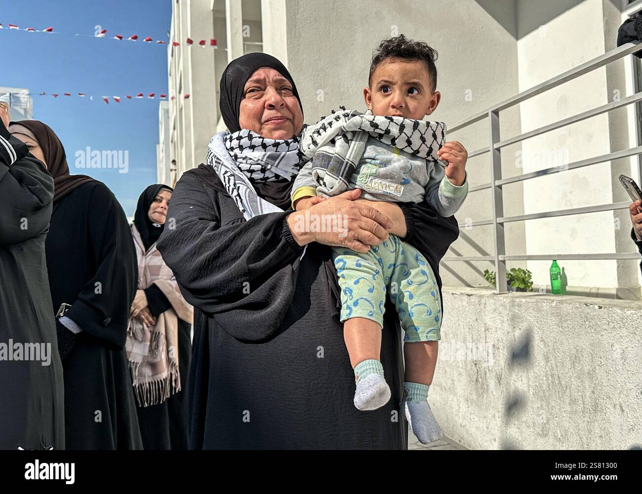 A Palestinian woman holds a child while celebrating the ceasefire in ...