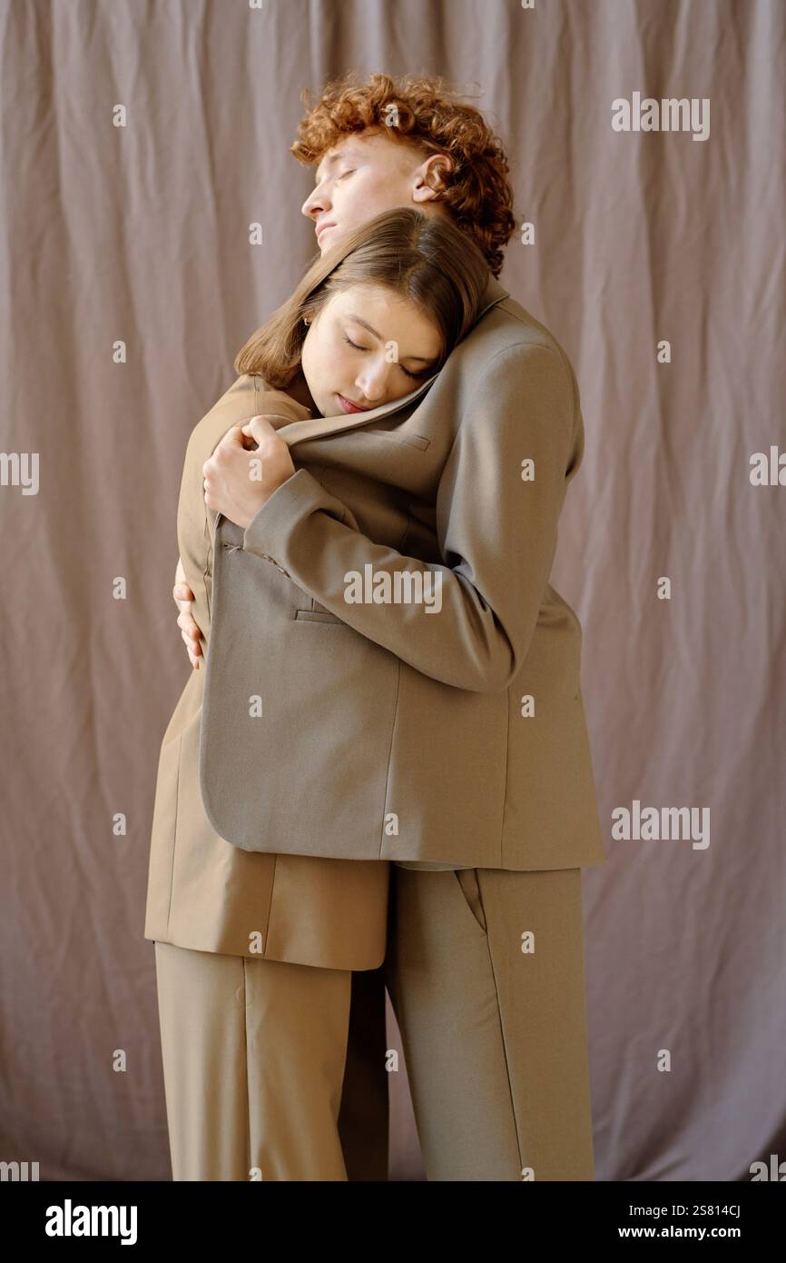 Vertical shot of delicate woman cuddling her strong man who protecting ...