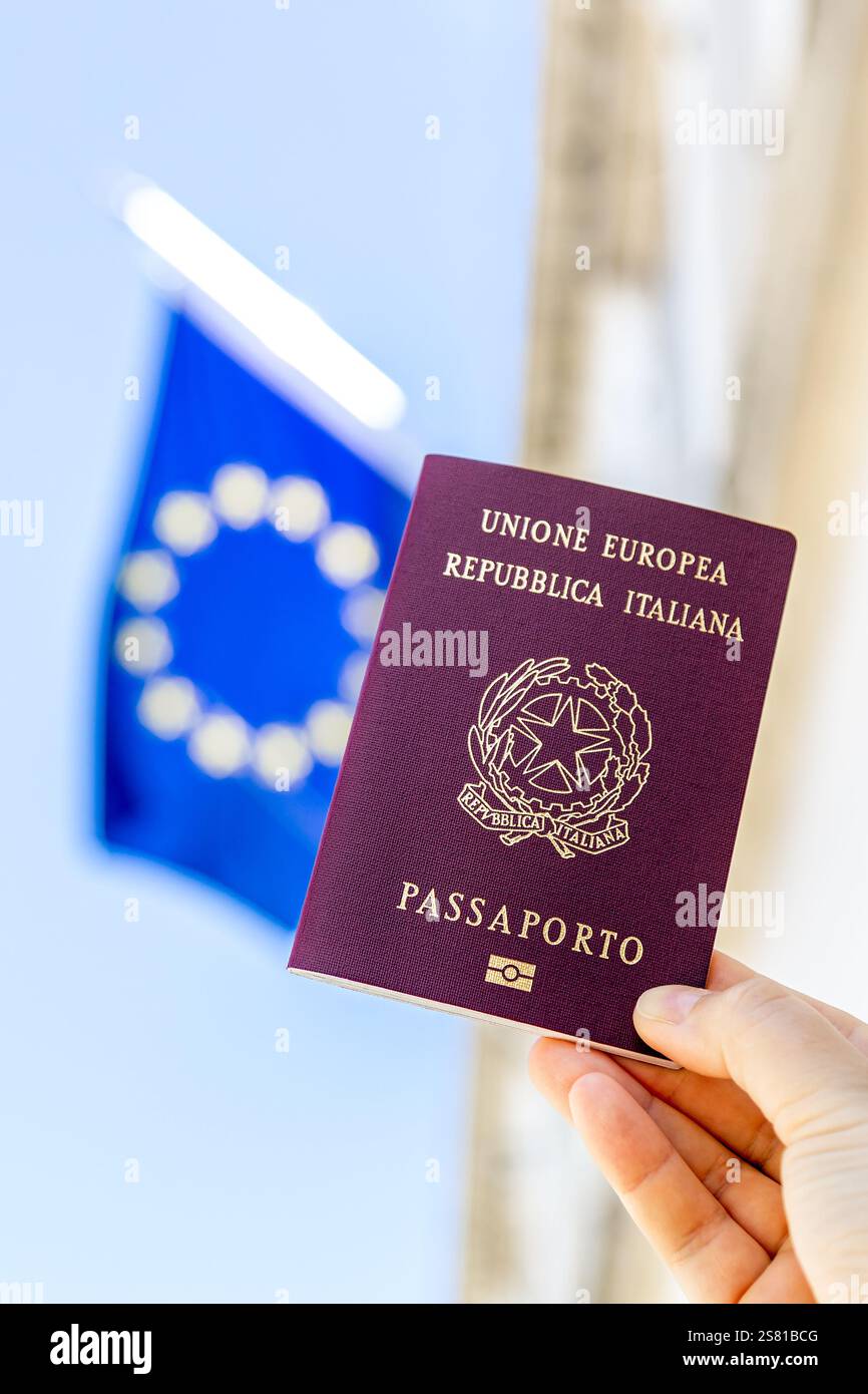 Hand holding Italian passport with European Union flag waving in the ...