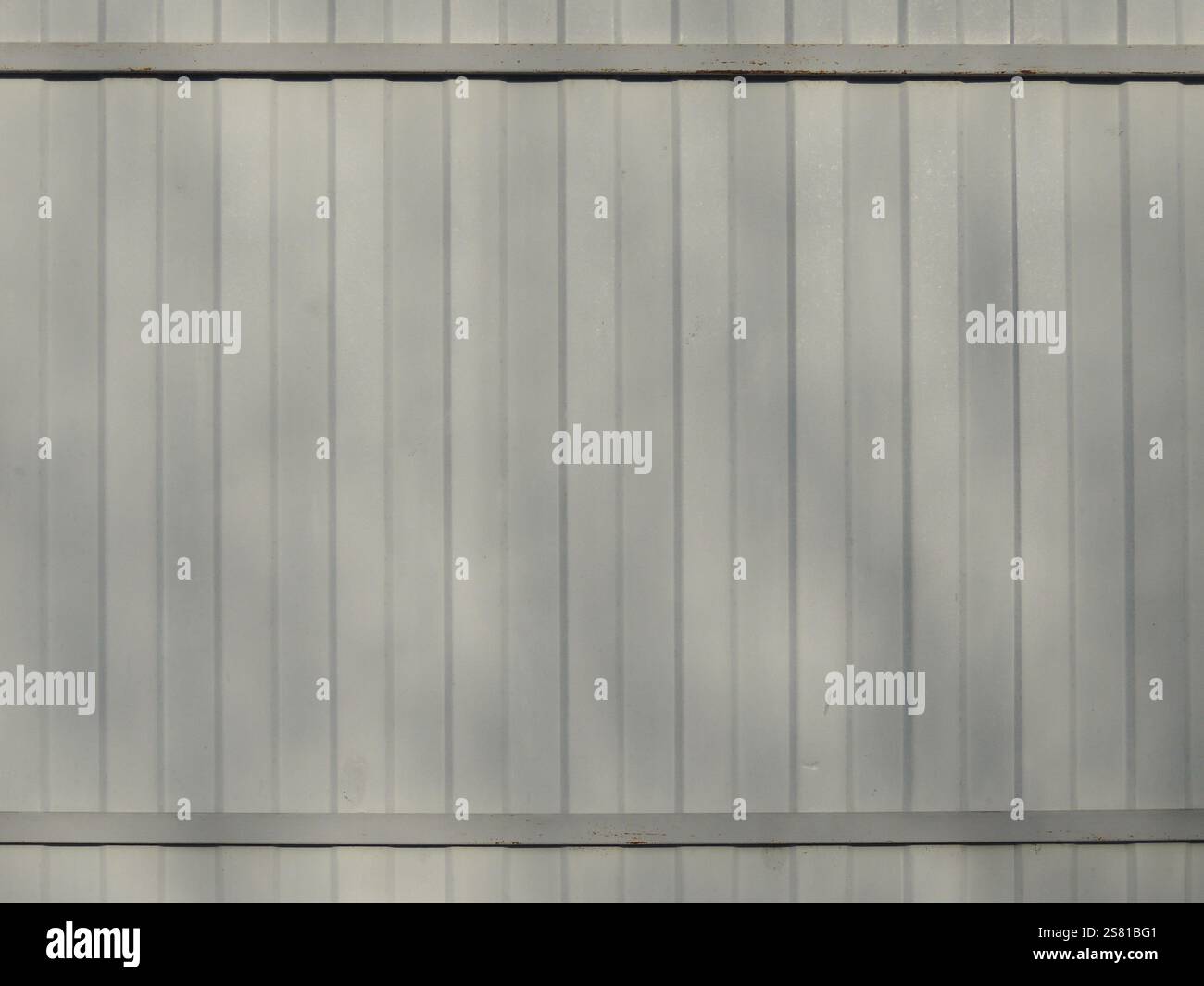 gray metal fence in soft sunlight with pale shadow spots, with vertical ...
