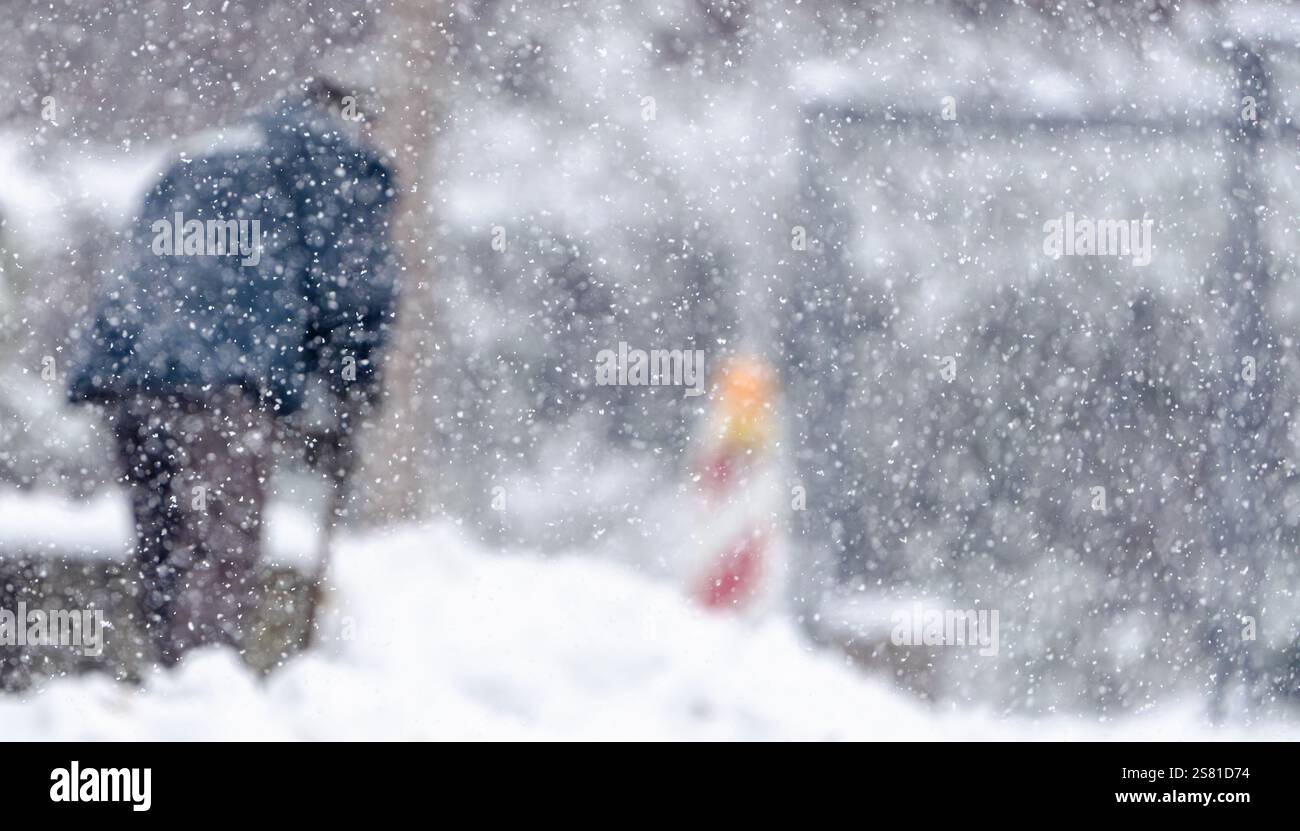 A man shovels snow in the snow. The snow is falling and the man is ...