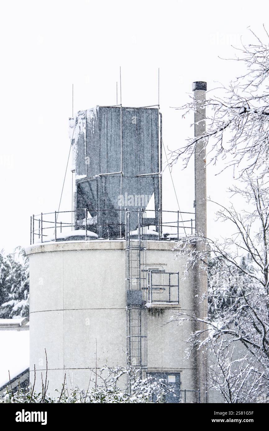 A snow covered tower with a ladder leading up to it. The tower is grey ...