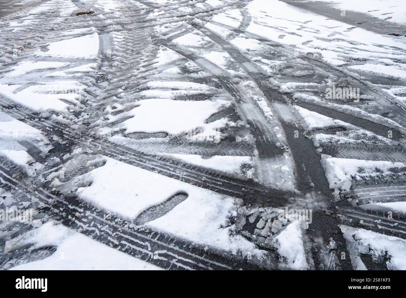 A snowy road with tire tracks in the snow. The tracks are in various ...