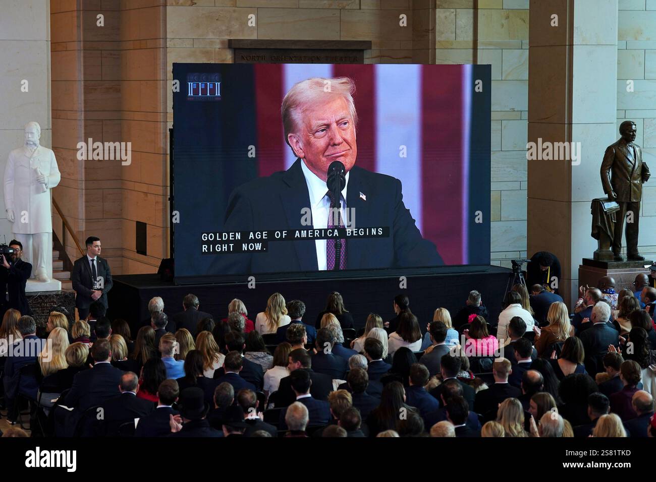 People watch the 60th Presidential Inauguration from Emancipation Hall, Monday, Jan. 20, 2025 ...