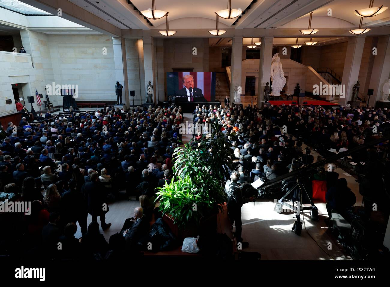 Guests and VIPs watch President Donald Trump speak on television ...