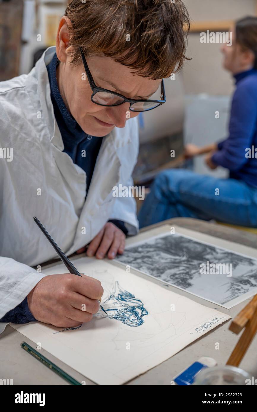 Two seated women painting during a drawing class in a studio with ...