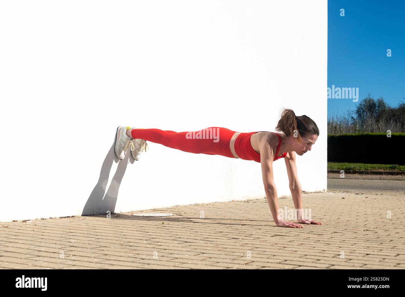 Athletic woman female performing plank exercise outdoors against white ...