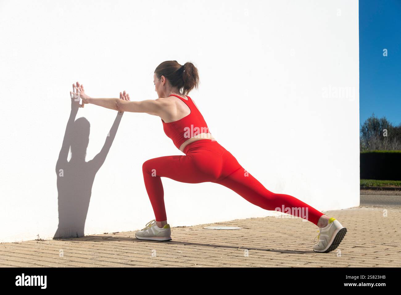 fit sporty woman performing a forward lunge stretch with her hands ...
