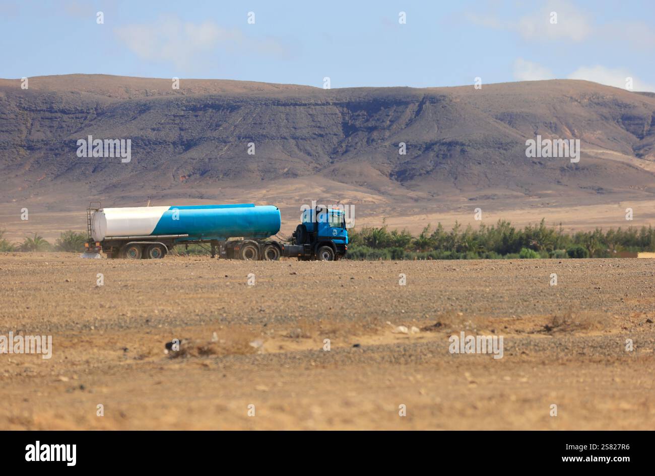 Water delivery tanker driving across the desert landscape of delivering ...