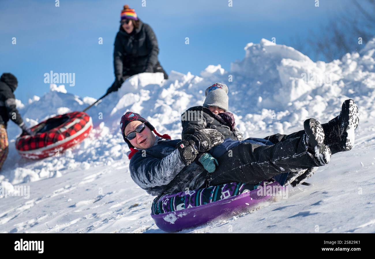 Kyle Foss holds his son Kasen as they slide behind Sherwood Heights ...