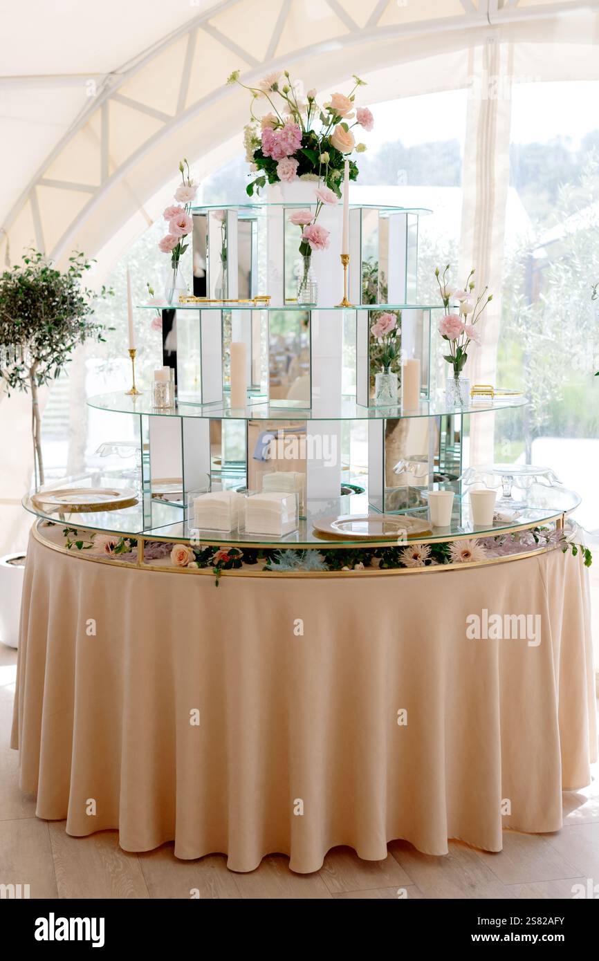 Elegant tiered serving stand adorned with pink flowers and candles ...