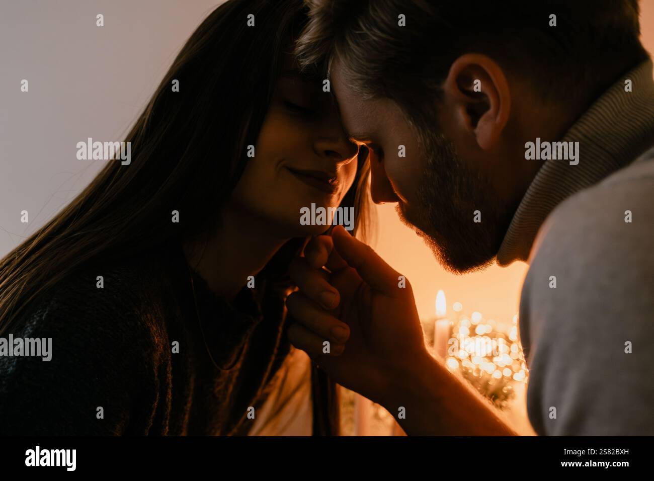 Couple sharing a romantic and intimate moment by candlelight in warm ...