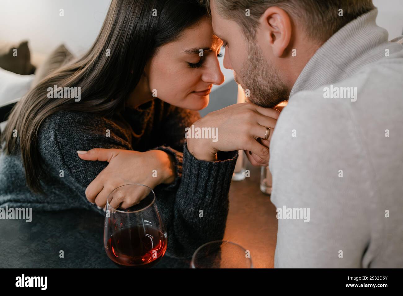 Romantic couple enjoying an intimate moment during dinner with red wine ...