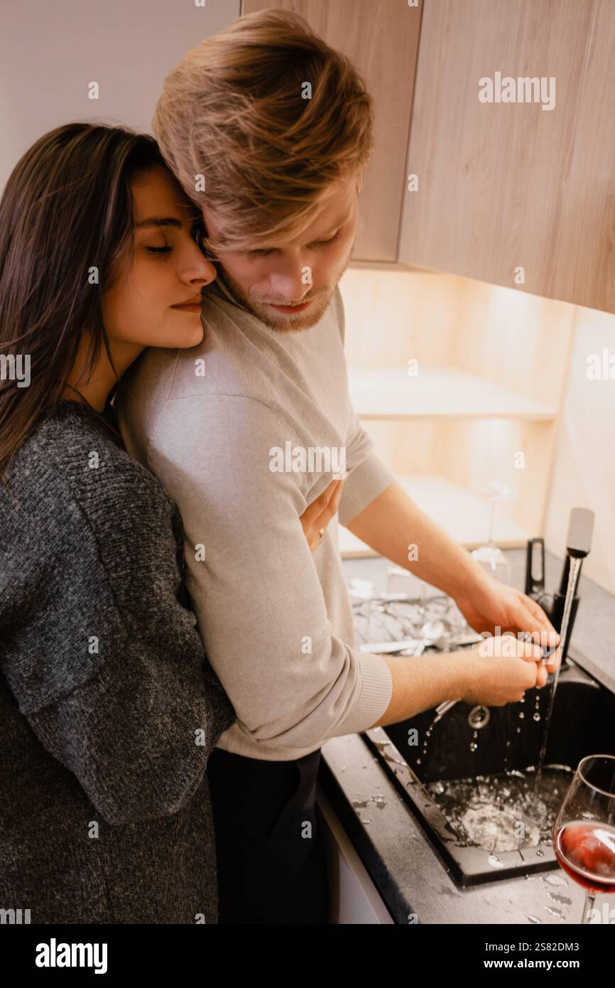 Romantic couple sharing an intimate moment while washing dishes ...