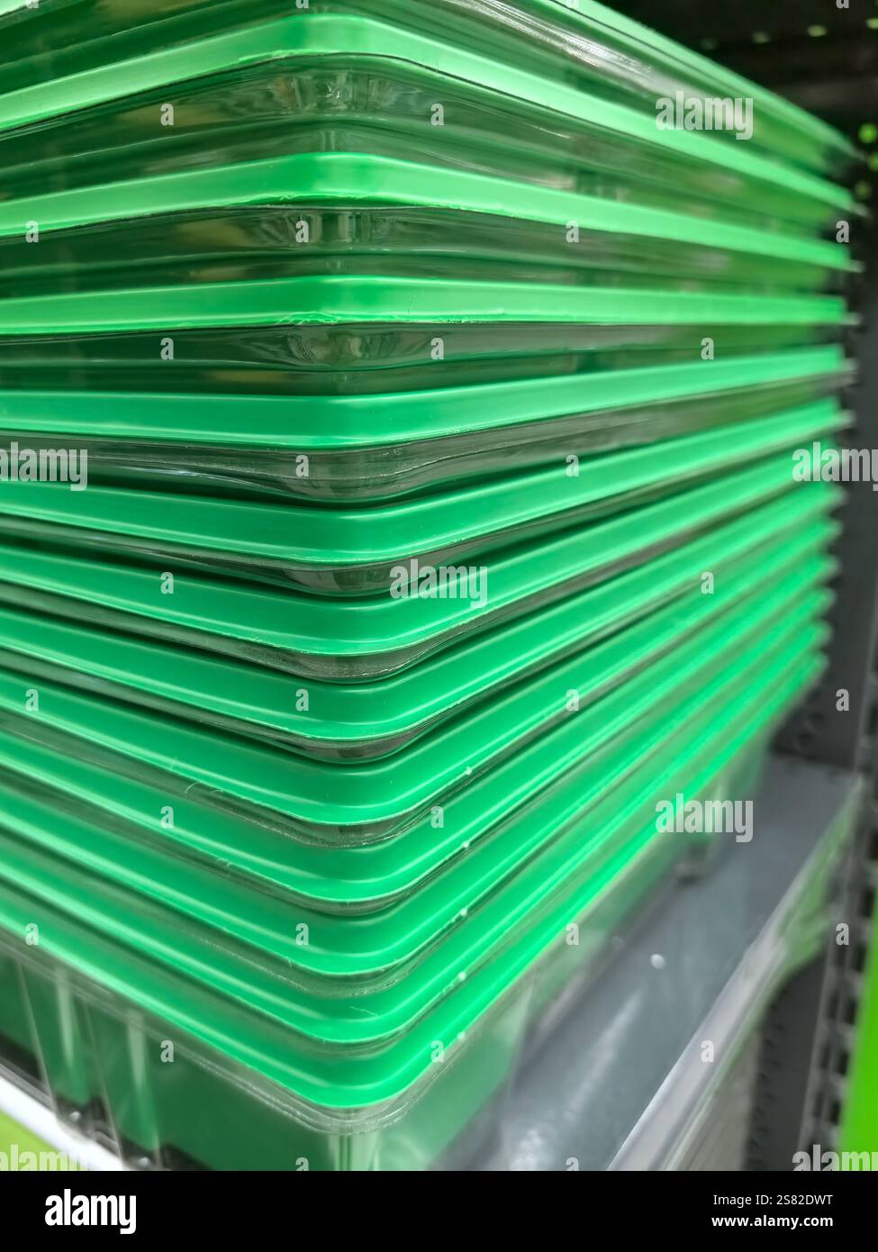 Multiple layers of vibrant green trays are neatly stacked on shelves in ...