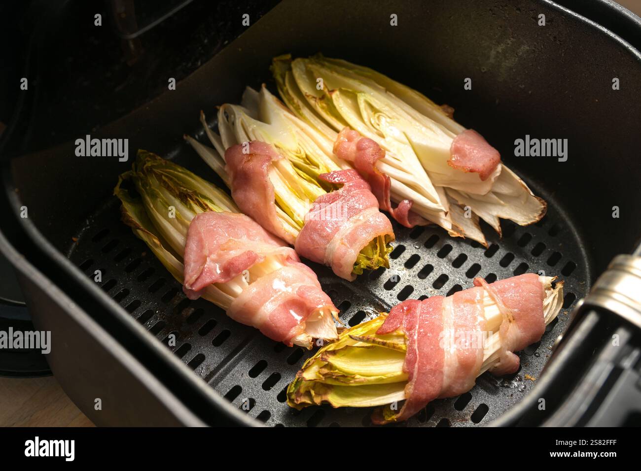 Chicory with bacon roasted in the black hot air fryer, kitchen utensil ...
