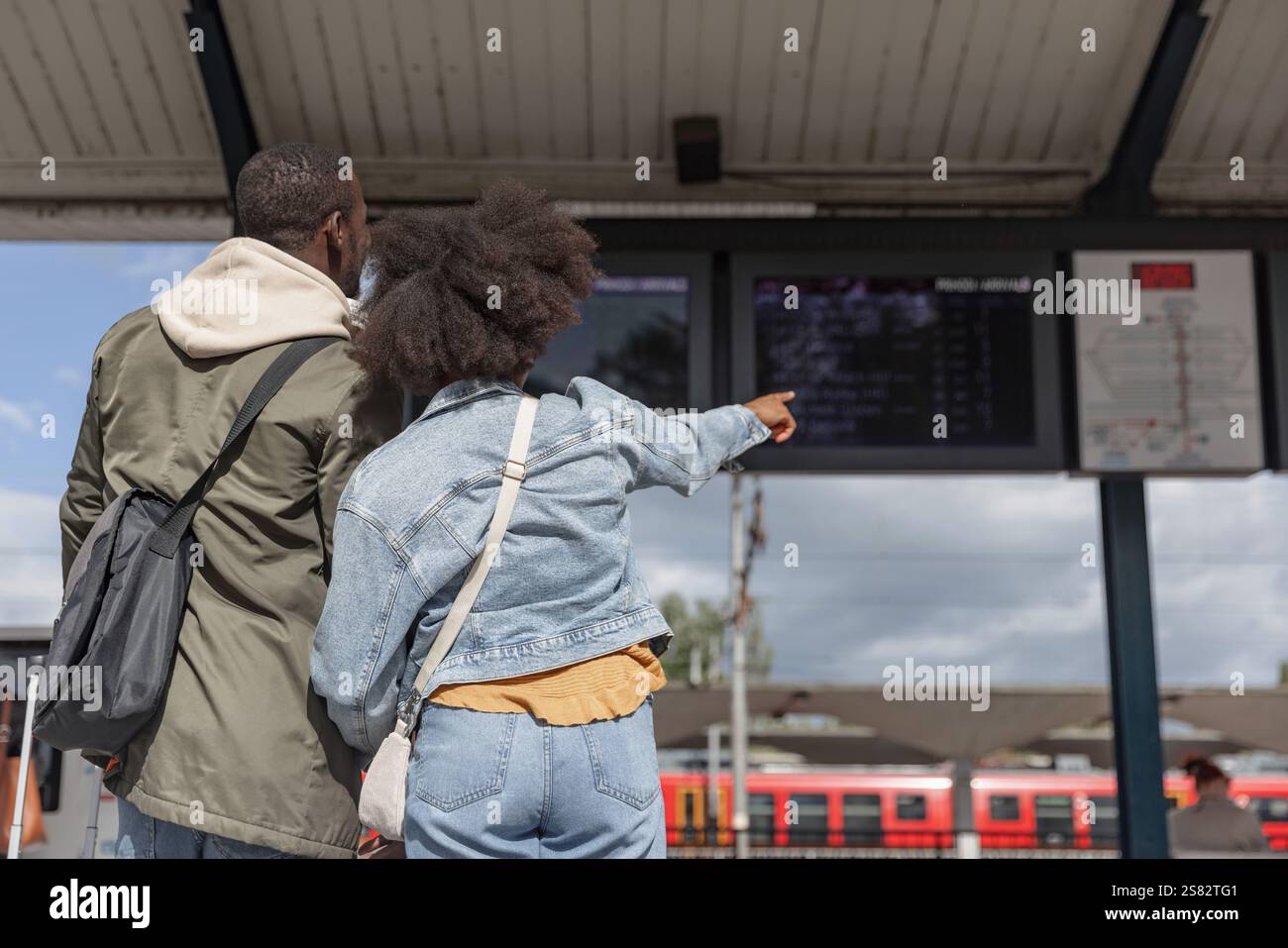 Two passengers, an African American couple looking at a train departure ...