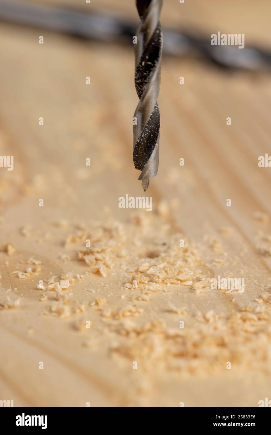 metal drill bit and pine wood board during operation, close up of pine ...